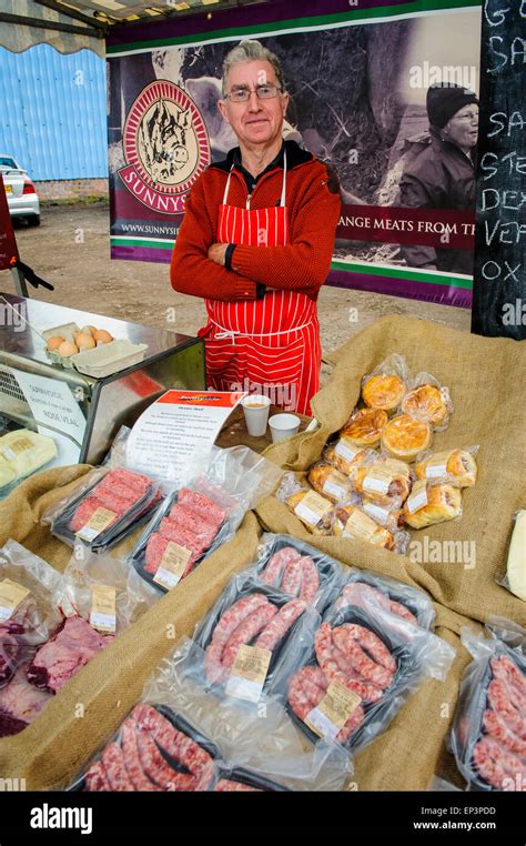 A Butcher Standing Behind His Stall Selling Meat At A Farmers Market In