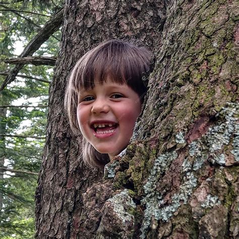 Premium Photo Portrait Of Cute Smiling Girl Amidst Tree Trunk