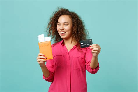 파란 청록색 벽 배경에 고립 된 여권 탑승권 티켓 신용 카드를 들고 캐주얼 복장에 즐거운 아프리카 소녀 사람들은 진심으로 감정 라이프 스타일 개념입니다 복사 공간을 모의