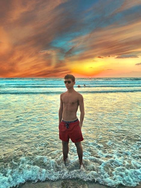 Premium Photo Full Length Of Shirtless Man Standing In Sea During Sunset