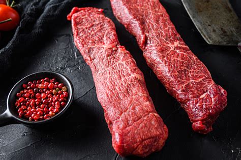 분홍색 후추와 로즈마리와 정육점 칼 근처 생 대리석 쇠고기 스테이크 검은 색 배경 측면 보기입니다 0명에 대한 스톡 사진 및