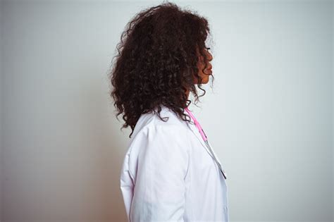 고립된 흰색 배경 위에 분홍색 청진기를 입은 아프리카 계 미국인 의사 여성은 자신감있는 미소로 자연스러운 얼굴로 프로필 포즈를