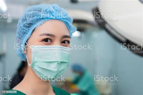 의료 마스크를 착용한 아시아 여성 외과 의사가 병원의 수술실에 서 있는 초상화 전문 외과 의사 팀 의료응급의료 서비스 개념