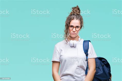 젊은 갈색 머리 학생 소녀 얼굴에 심각한 표정으로 격리 된 배경 위에 배낭와 헤드폰을 착용 간단 하 고 카메라를 보고 자연