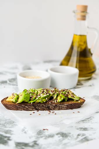 콘크리트 배경에 건강한 아보카도 토스트 통곡물 빵 참깨 아마 씨 올리브 오일 비건 케토 다이어트 건강한 식생활 트렌디한 과카몰리