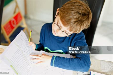 집에서 안경을 쓰고 귀여운 학교 아이 소년의 초상화 숙제를 만들기 작은 집중 된 아이는 실내에서 다채로운 연필로 씁니다 초등
