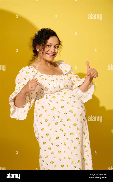 Beautiful Pregnant Woman Dressed In Summer Sundress Points Fingers At