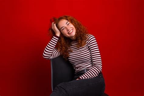 Premium Photo Photo Of Foxy Young Woman Sitting In Chair And Smiling At Camere Over Red