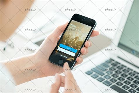 عکس گوشی در دست خانم در حال کار با گوشی و کامپیوتر عکس با کیفیت و