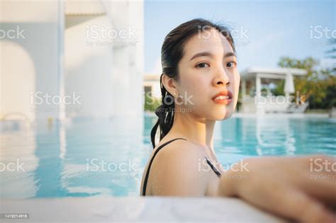 아름다운 여성의 초상화는 수영장에서 카메라를 바라보고 열대 스파에서 여름 방학에 카메라를 보면서 휴식을 취하며 얼굴에 선 스크린