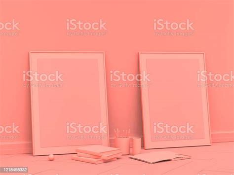 책과 펜이 있는 단색 단일 분홍색 색상의 방 3d 렌더링 측면 보기로 바닥에 2개의 수직 빈 포스터 프레임 0명에 대한 스톡