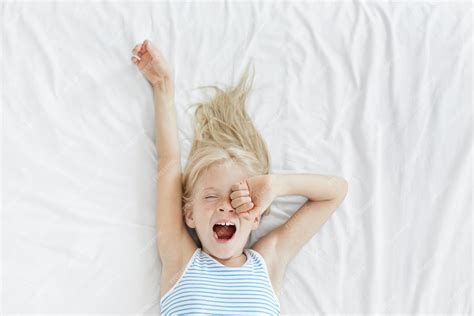 Linda Niña Rubia Que Se Extiende En La Cama Blanca Foto Gratis