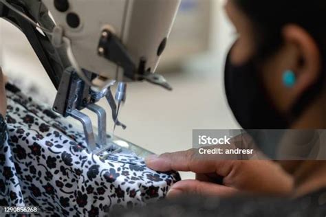 섬유 공장에서 일하는 한 여성이 옷을 바느질하고 얼굴 마스크를 쓰고 클로즈업 25 29세에 대한 스톡 사진 및 기타 이미지