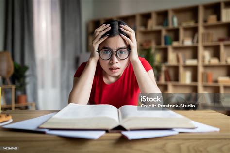 실망한 충격을 받은 사춘기 아시아 여학생이 안경을 쓰고 책을 읽고 손으로 머리를 잡고 시험에 대한 스톡 사진 및 기타 이미지