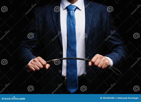 Male Dominant Businessman In A Suit Holding A Leather Whip Flogger For