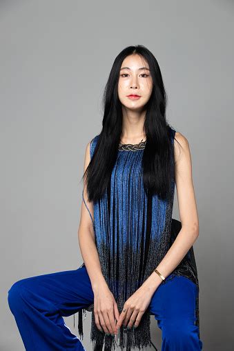 긴 검은 직선 머리를 가진 아시아 트랜스젠더 여성 카메라를보십시오 여성은 앉아서 블루 패션 관능적 인 섹시한 드레스 회색 배경 고립 된 복사 공간을 착용합니다 패션에 대한