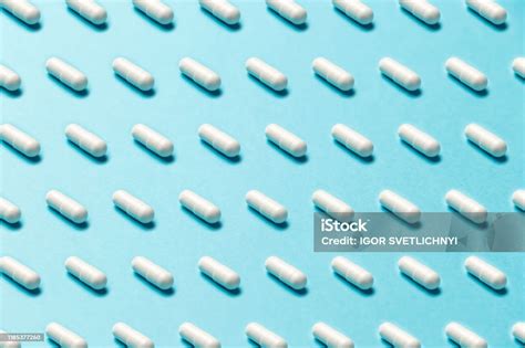 明るい水色の背景に薬薬の丸薬錠剤やカプセルで作られたトレンディなパターン医学の創造的な概念カラフルな紙を背景にしたミニマルなスタイルトレンディ