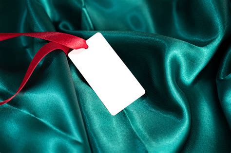 고급스러운 짙은 녹색 새틴 배경에 빨간 리본 끈이 있는 백서 가격표 모형 크리스마스에 딱 맞습니다 0명에 대한 스톡 사진 및 기타 이미지 Istock