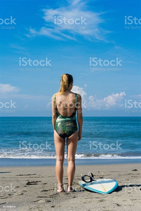 여성 서퍼 서핑 보드와 함께 해변에 서 서 고 바다 보고의 뒷면 관광에 대한 스톡 사진 및 기타 이미지 관광 관광 리조트