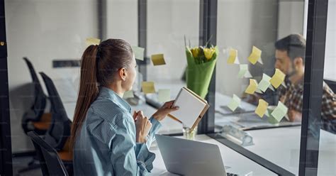 나선형으로 묶인 공책을 손에 들고 의자에 앉아 유리 벽을 통해 동료를 바라보는 여자 사진 Unsplash의 앉아 이미지
