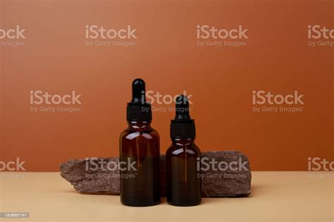 갈색 배경에 대한 돌 옆에 스킨 케어를위한 세럼이나 오일이있는 두 개의 어두운 유리 병 0명에 대한 스톡 사진 및 기타 이미지
