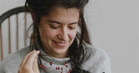 집에서 귀여운 고양이와 함께 크리스마스 화환 만들기 휴일 강림 빨간 열매와 녹색 가지를 들고 사랑스러운 고양이 도우미와 함께 크리스마스 화환을 만드는 행복한 여자 세련