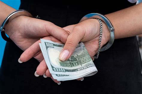 Female Hands In Handcuffs Hold Dollars Isolated On Blue Stock Image