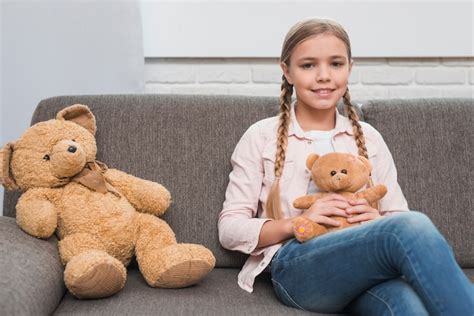Portrait D une Jeune Fille Souriante Assise Avec Petit Ours En Peluche Sur Un Canapé Gris