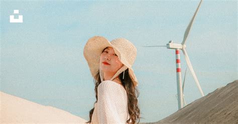 하얀 드레스와 모자를 쓴 여자가 모래 위에 서 있다 사진 Unsplash의 무료 모자 이미지