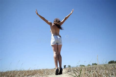 Back View Of A Unrecognized Topless Woman With Arms Raised In