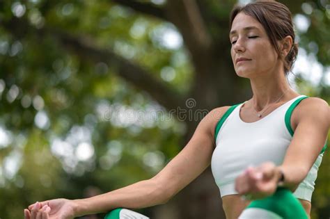 Woman In Green Sportswear Sitting In A Lotus Pose And Meditating Stock