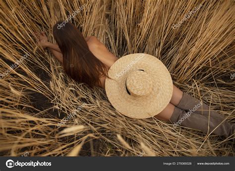Femme nue couchée sur un champ avec un chapeau image libre de droit par