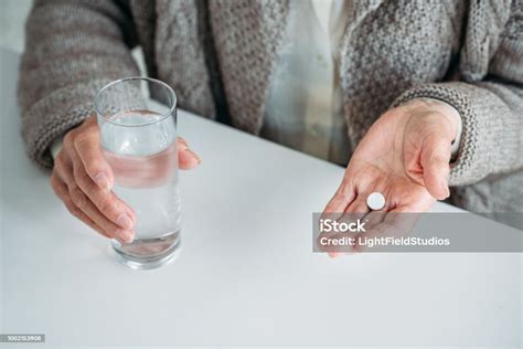 알 약 및 집에서 혼자 테이블에 앉아 손에 물 유리 고위 여자의 부분 보기 가리기에 대한 스톡 사진 및 기타 이미지 가리기