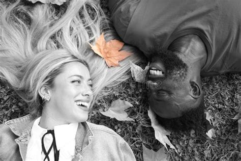 Happy Interracial Couple Lying On The Grass Couple Looks At Each Other