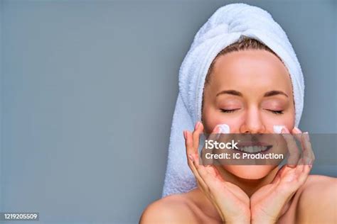 Gadis Dengan Mata Tertutup Dengan Senyum Handuk Mengoleskan Krim Putih