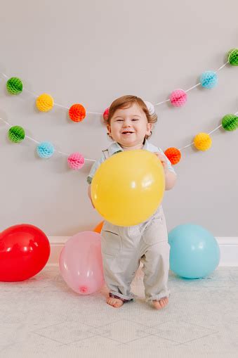 첫 번째 생일을 축하하는 재미있는 백인 아기 소년 화려한 풍선과 흥분 감정적 인 아이 아이 유아 집에서 실내에서 이벤트 또는