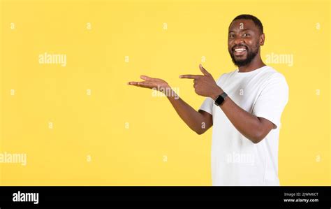 Black Guy Pointing At Hand Holding Invisible Object Yellow Background Stock Photo Alamy