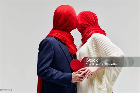 알아볼 수 없는 커플 남자와 여자의 초상화 패브릭 머리와 흰색 스튜디오 배경에 빨간 종이 하트를 들고 있습니다 20 24세에