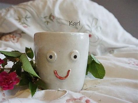 A Coffee Cup With A Face On It Next To Some Flowers