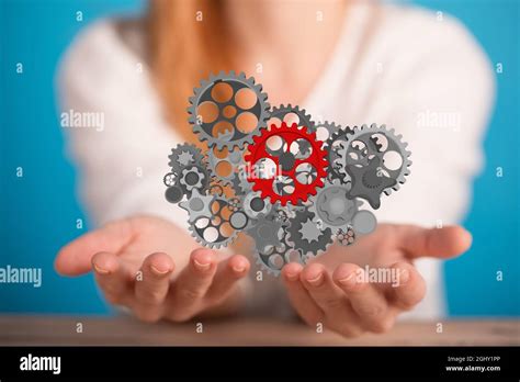 3d rendering of red and gray gears hovering over a female s hands stock