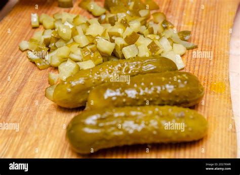 Womens Hands Cut Pickles Into Cubes On A Wooden Cutting Board In The Kitchen Close Up Stock