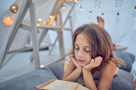 거실 안에 있는 집에서 만든 텐트 아래에서 고전 책을 읽는 10세 소녀 10에 대한 스톡 사진 및 기타 이미지 10 가정