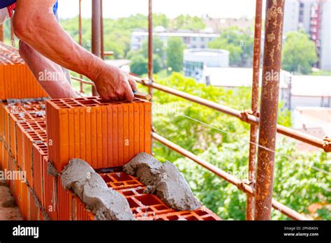 Mason Bricklayer Worker Is Using Red Blocks To Mount A Wall Next The