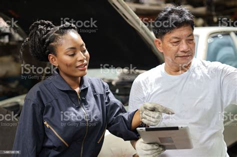 제복을 입은 기술자 자동차 정비사 남성과 여성이 수리 차고 역에서 유지 보수 차량 서비스를 확인하고 있다 태블릿 점검 고장 차량을 사용하는 작업자 자동차 센터 수리 서비스의