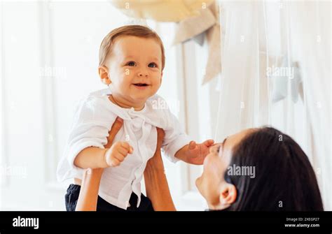 A Young Beautiful Mom Lifts Her Cute Little Boy In Her Arms An