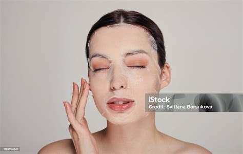 눈을 감고 보습 얼굴 마스크와 전체 입술을 가진 젊은 아름다운 부드러운 프레이티 소녀 회색 배경입니다 아래를 내려다 본다 공간을