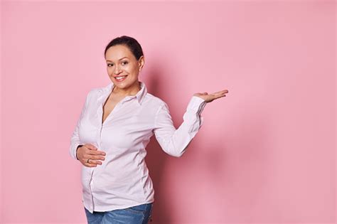 행복한 임산부가 배를 부드럽게 만지고 카메라에 미소를 짓고 손바닥에 상상의 카피 광고 공간을 들고 있다 라틴 아메리카 히스패닉