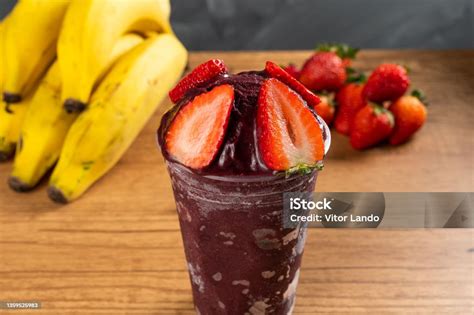 브라질 냉동 아사이 베리 아이스크림 스무디 에 플라스틱 컵 딸기 나무 책상과 과일이 있는 회색 여름 배경에 있습니다 메뉴 및