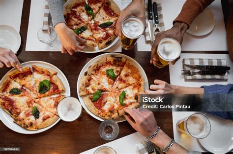 맛있는 이탈리아 피자와 맥주 한 잔을 들고 있는 사람들의 손은 알아볼 수 없는 다인종 그룹이 있는 탑 뷰 테이블 마르게리타
