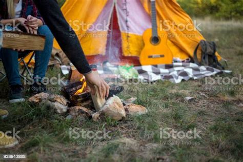 아름 다운 커플 앉아 캠프 파이어 주위에 캠핑 텐트와 배경에 남자 막대기로 화재 제스처 건강한 생활방식에 대한 스톡 사진 및 기타 이미지 Istock